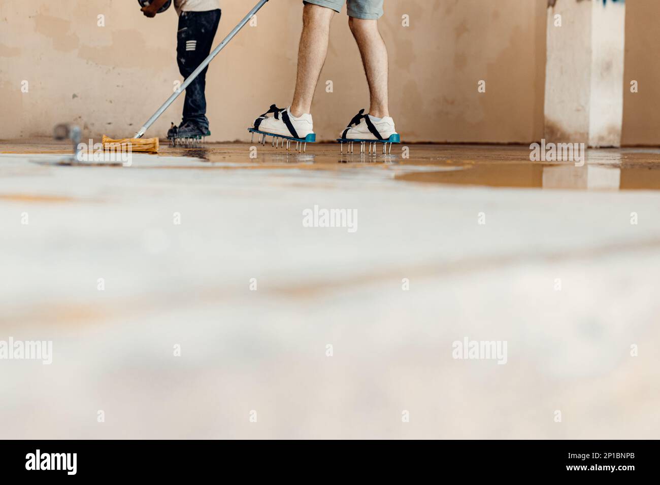 Worker applies floor primer with special tool Stock Photo - Alamy