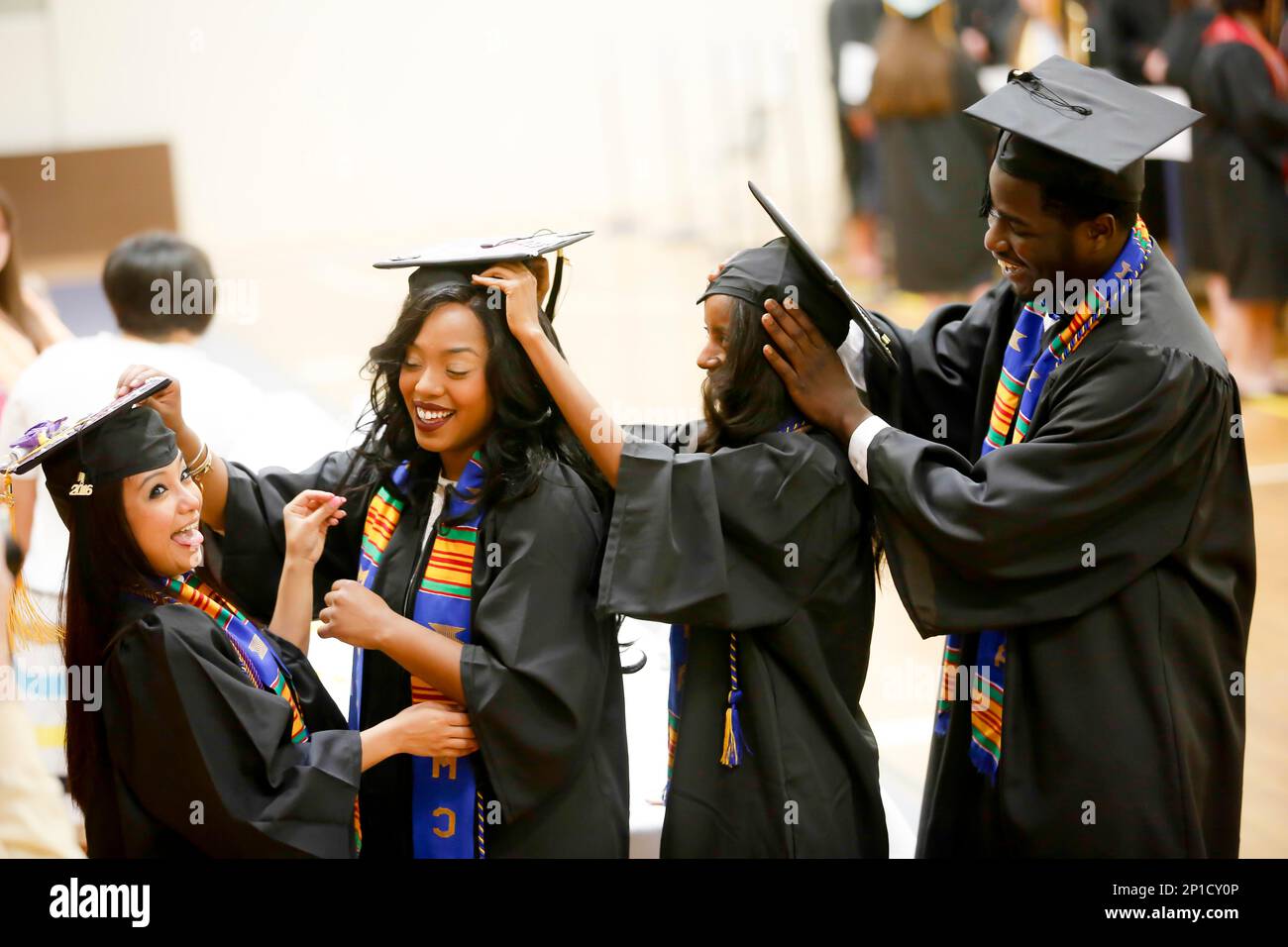 Graduates help each other out with their caps before marching to the ...