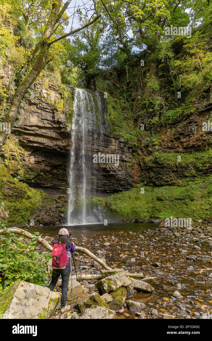 Photographer taking images of a beautiful waterfall in a small valley ...