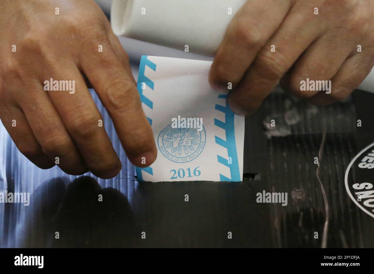 A Filipino man places the receipt of his vote in the box at a polling ...