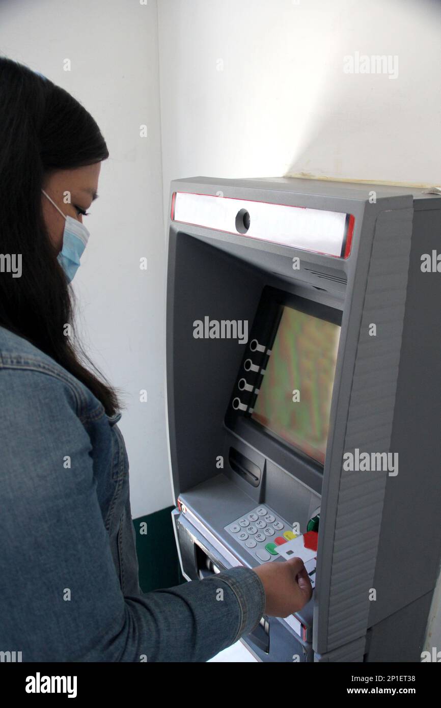 Latin woman with protection mask clinical use in ATM withdrawing money ...