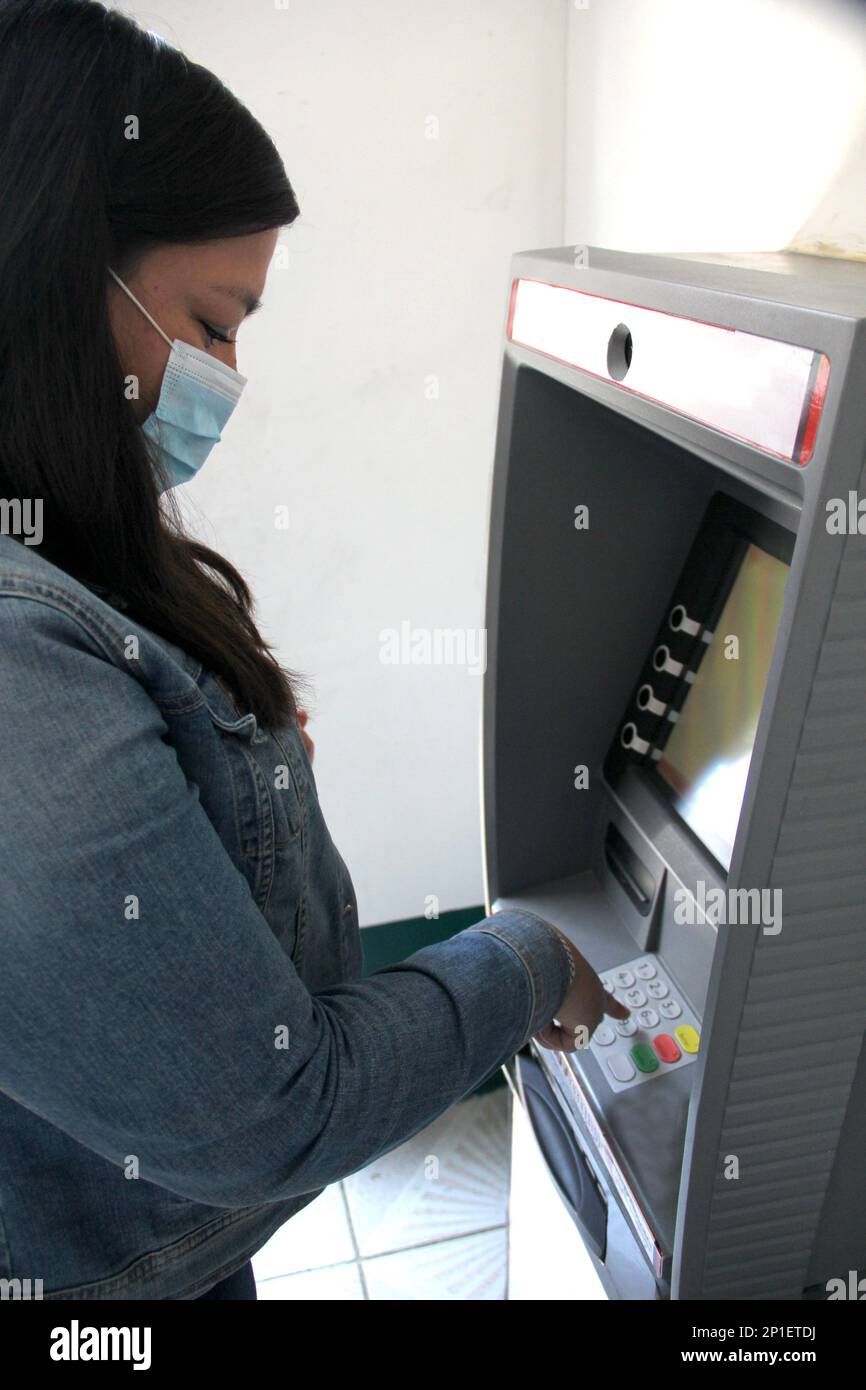 Latin woman with protection mask clinical use in ATM withdrawing money ...