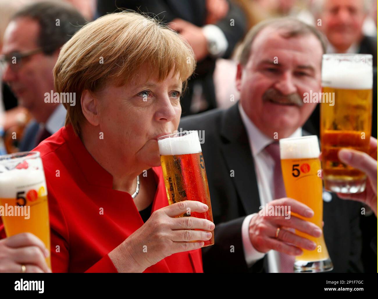 German Chancellor Angela Merkel, left, drinks beer during the 500th ...
