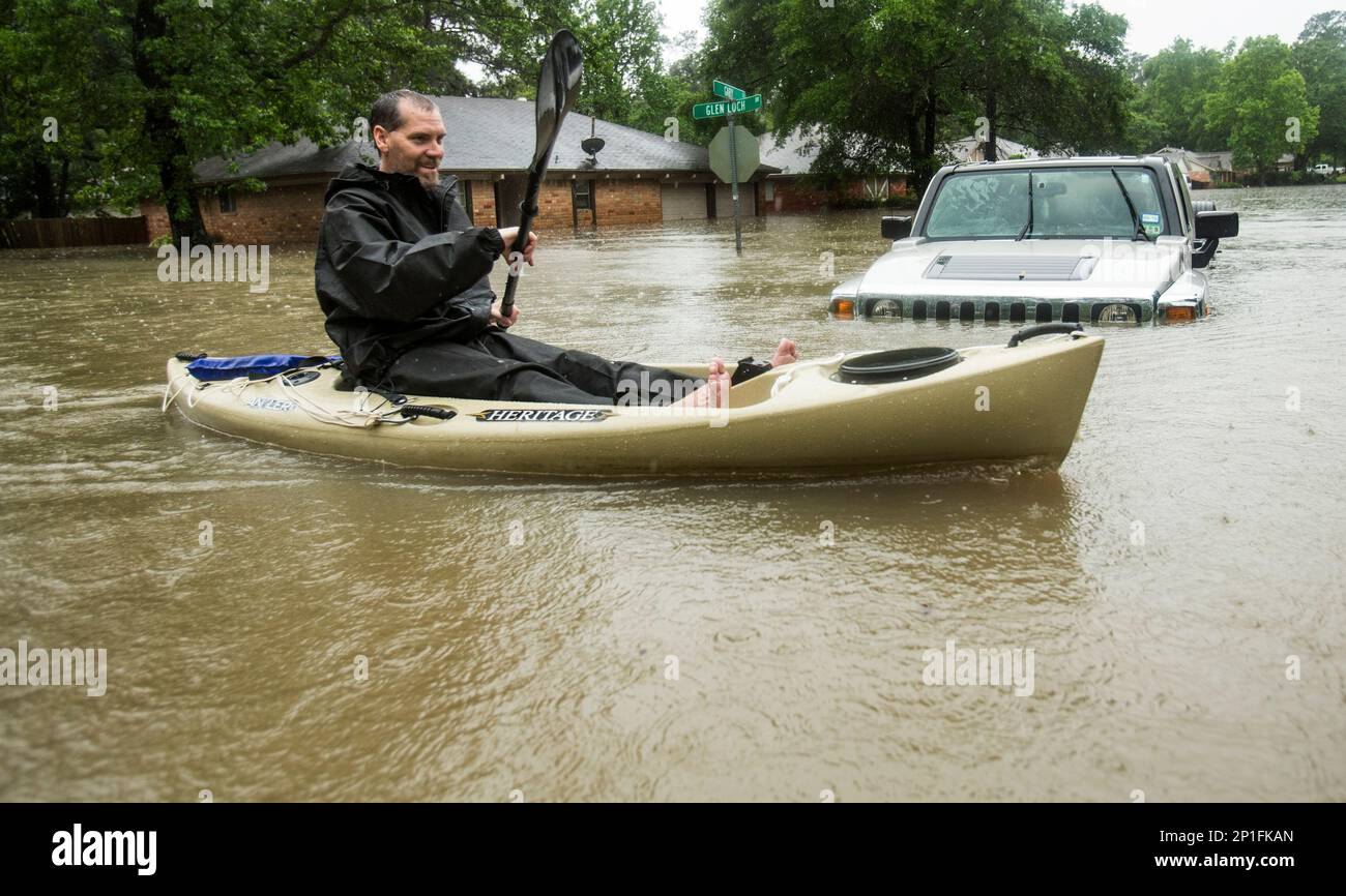 Kyle Lester paddles past a submerged SUV as he looks for residents to ...