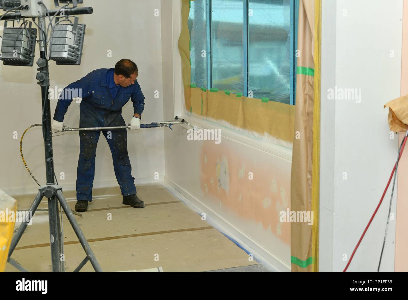 A painter applies an acrylic primer coat to the interior walls of a ...