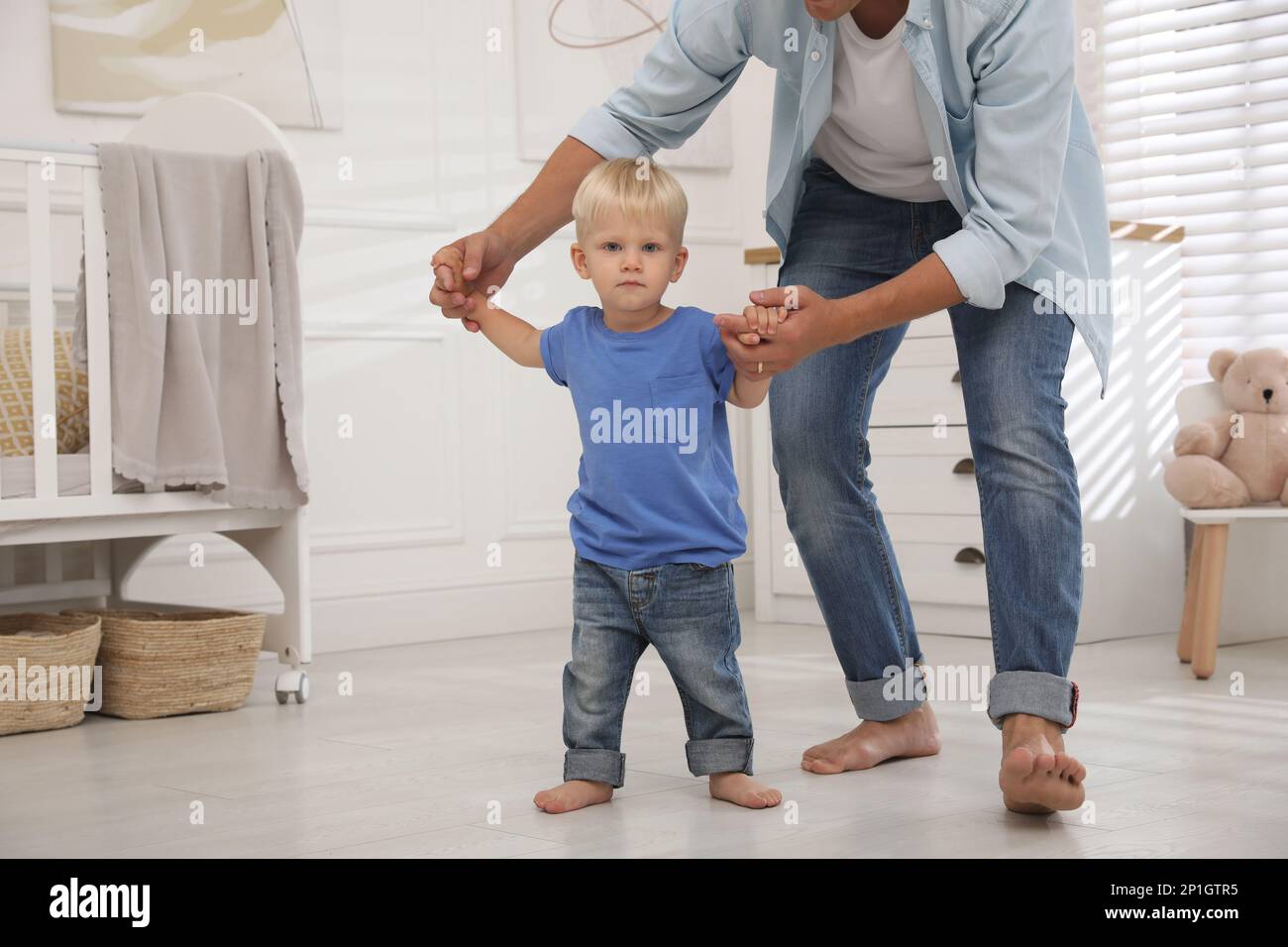 Little boy walking with father's help in nursery Stock Photo - Alamy