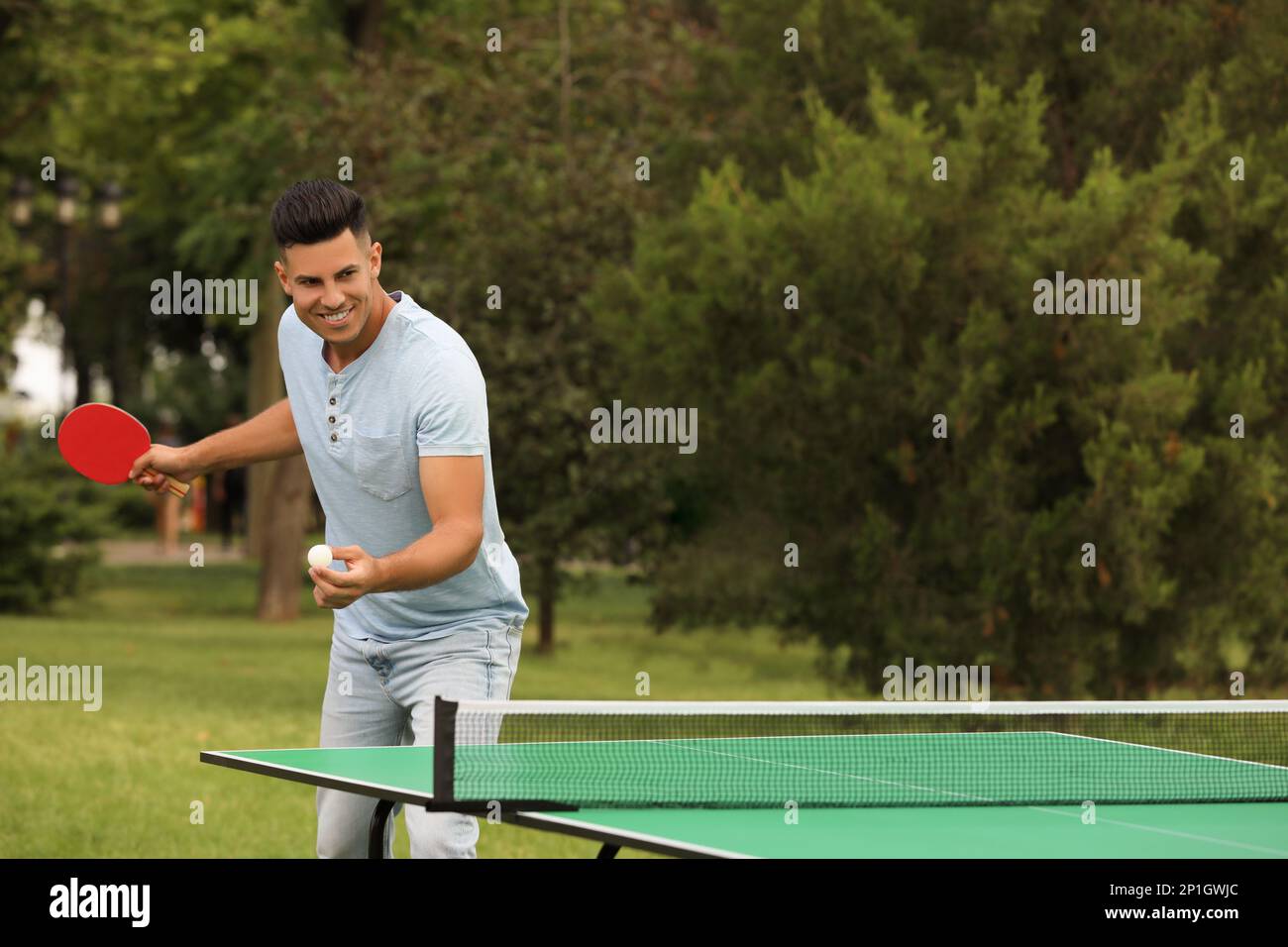 Happy man playing ping pong outdoors on summer day Stock Photo - Alamy