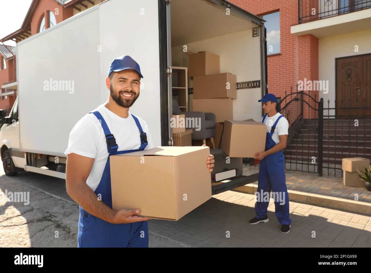 Workers unloading boxes from van outdoors. Moving service Stock Photo ...