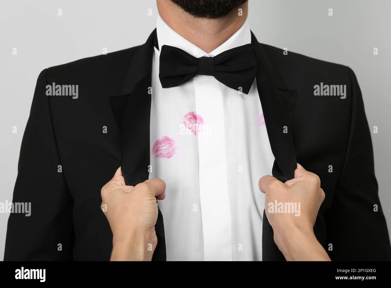 Woman grabbing her husband by suit jacket due to lipstick kiss marks on ...
