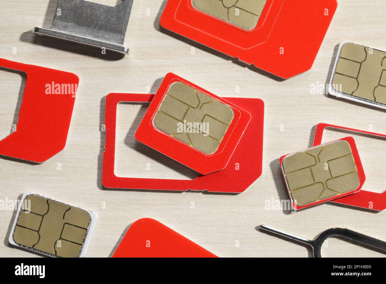 Different SIM cards, ejector and tray on wooden background, flat lay ...