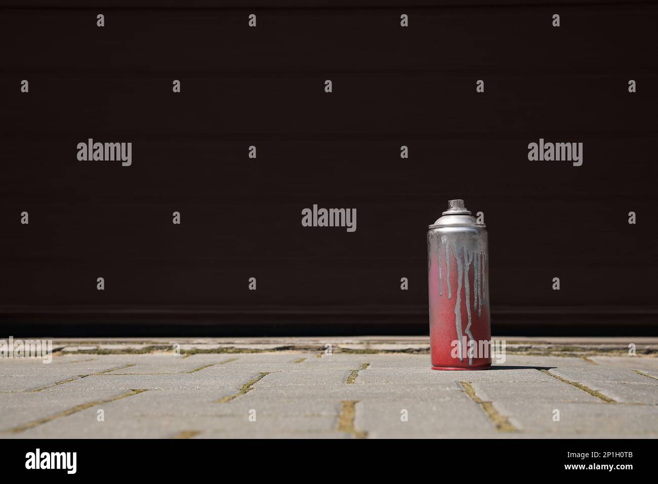 Used can of spray paint on pavement near black wall outdoors, space for ...
