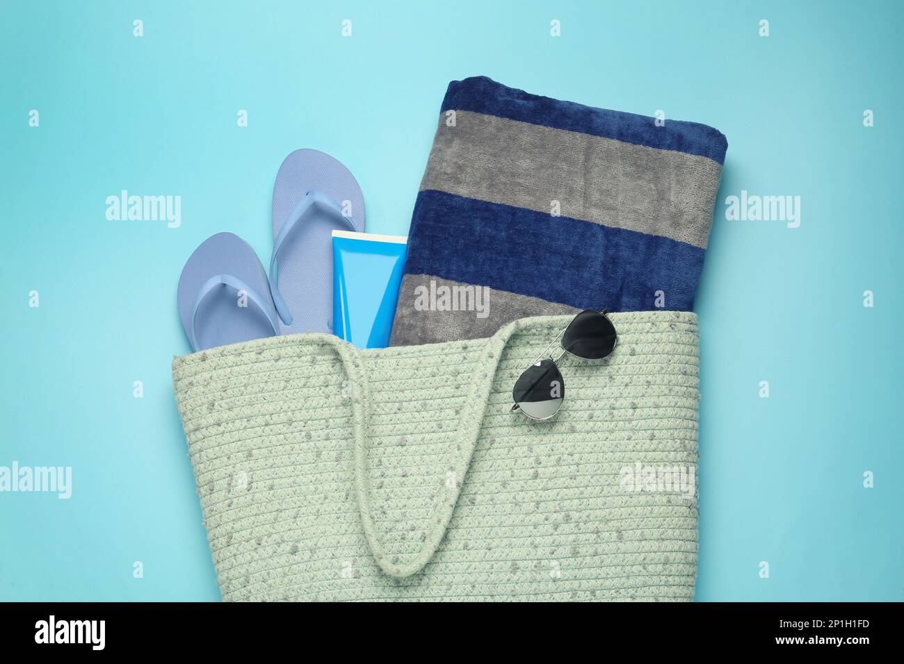 Beach bag with towel, flip flops, sunglasses and sun protection product ...