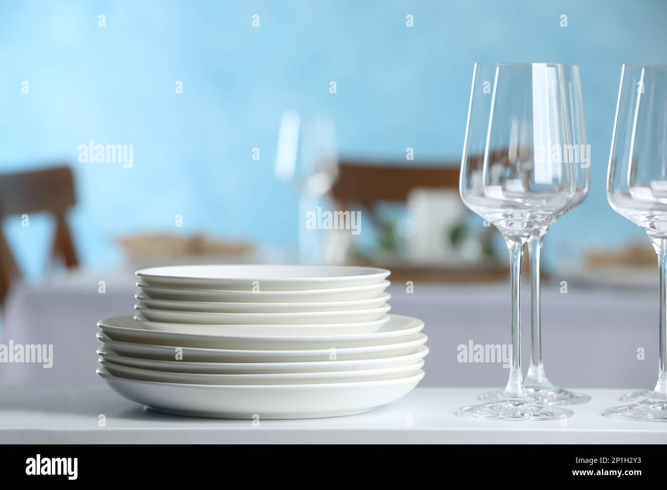 Stacked clean dishes and glasses on white shelf indoors Stock Photo - Alamy