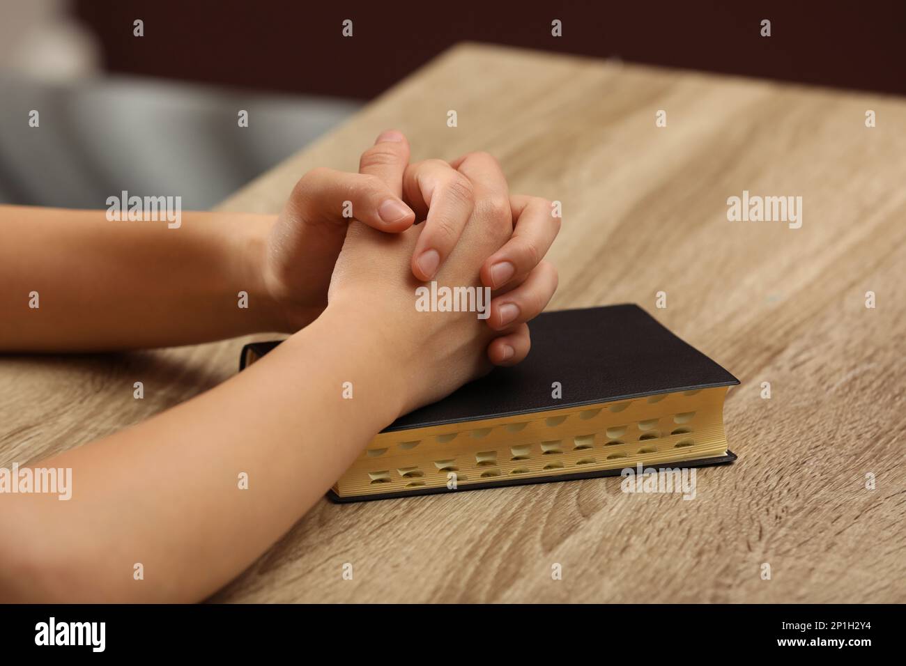 Religious woman praying over Bible at wooden table indoors, closeup ...