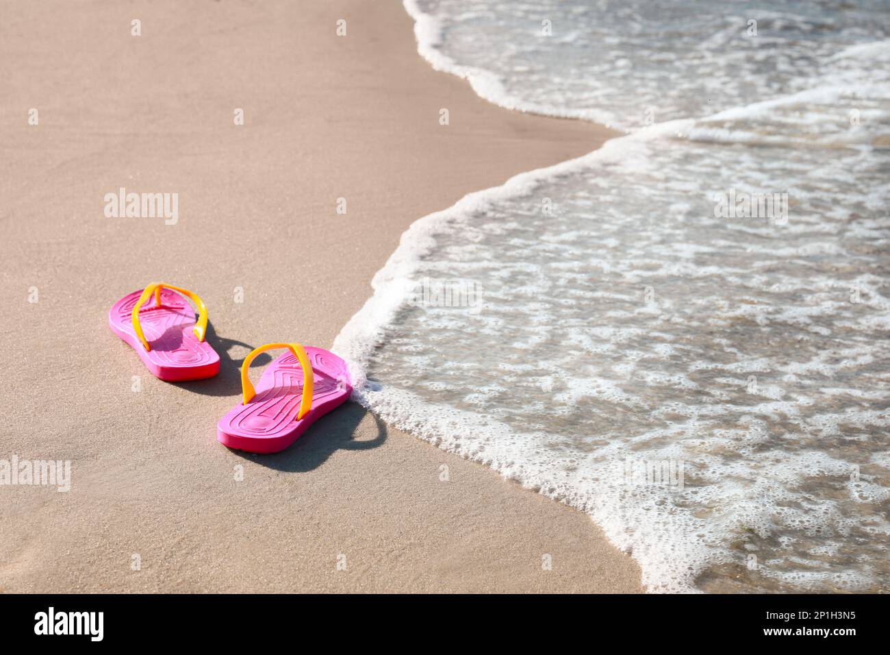 Pair of stylish flip flops on beach Stock Photo - Alamy