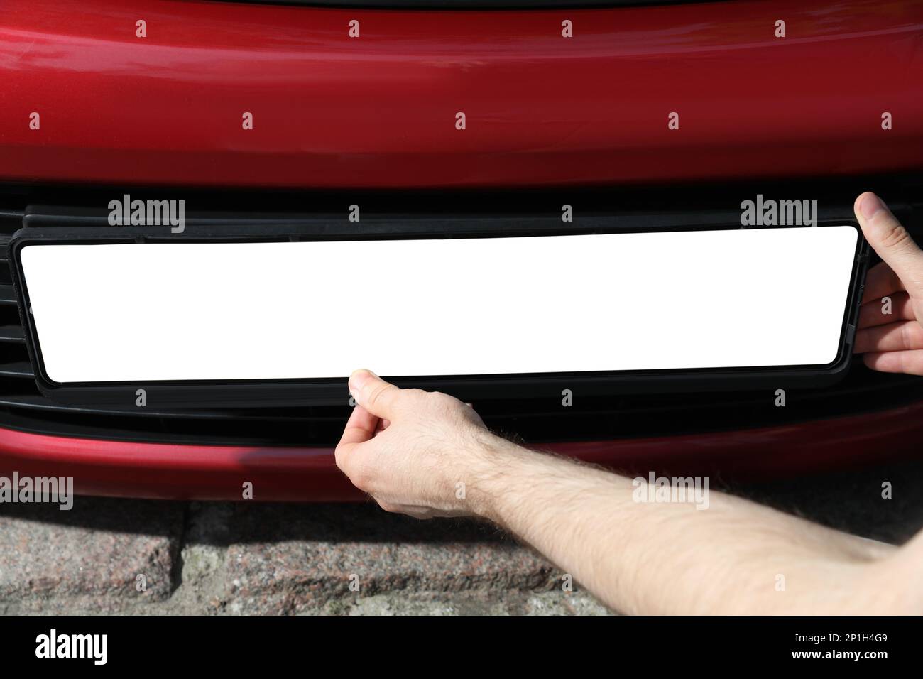Man installing vehicle registration plate outdoors, closeup. Mockup for ...
