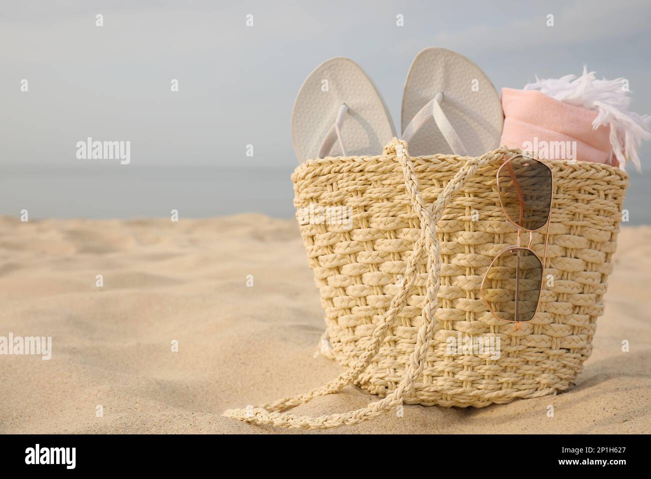 Beach bag with flip flops, towel and sunglasses on sandy seashore ...