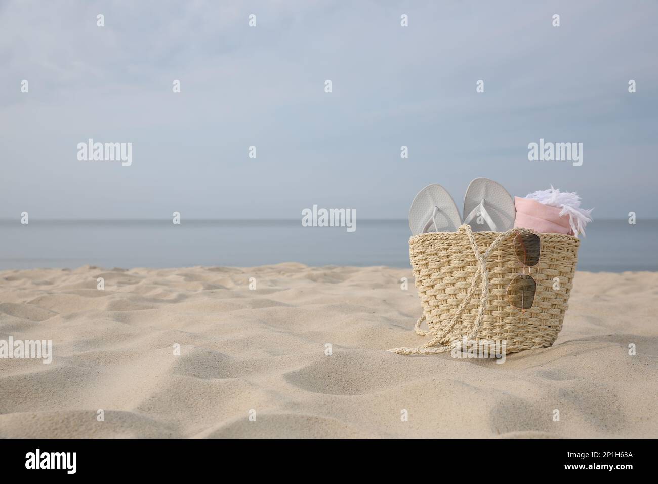 Beach bag with flip flops, towel and sunglasses on sandy seashore ...