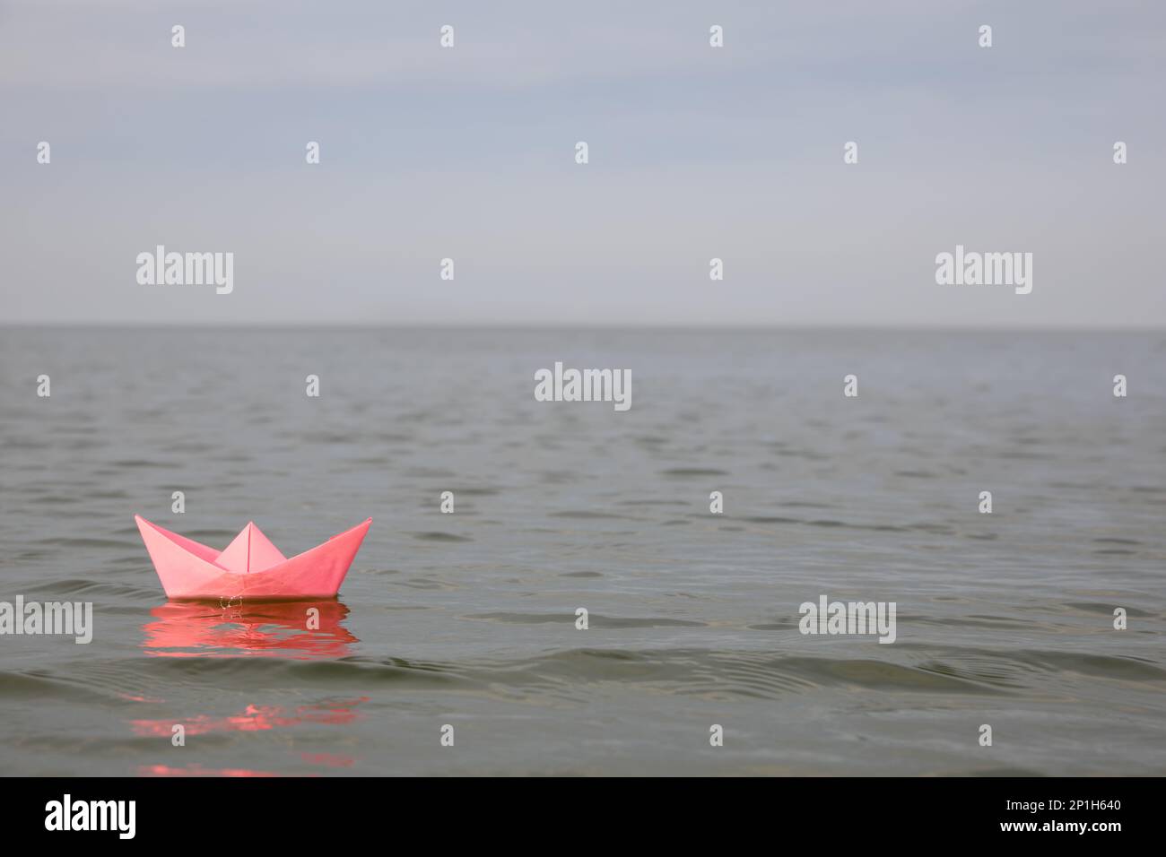 Pink paper boat on water surface, space for text Stock Photo - Alamy