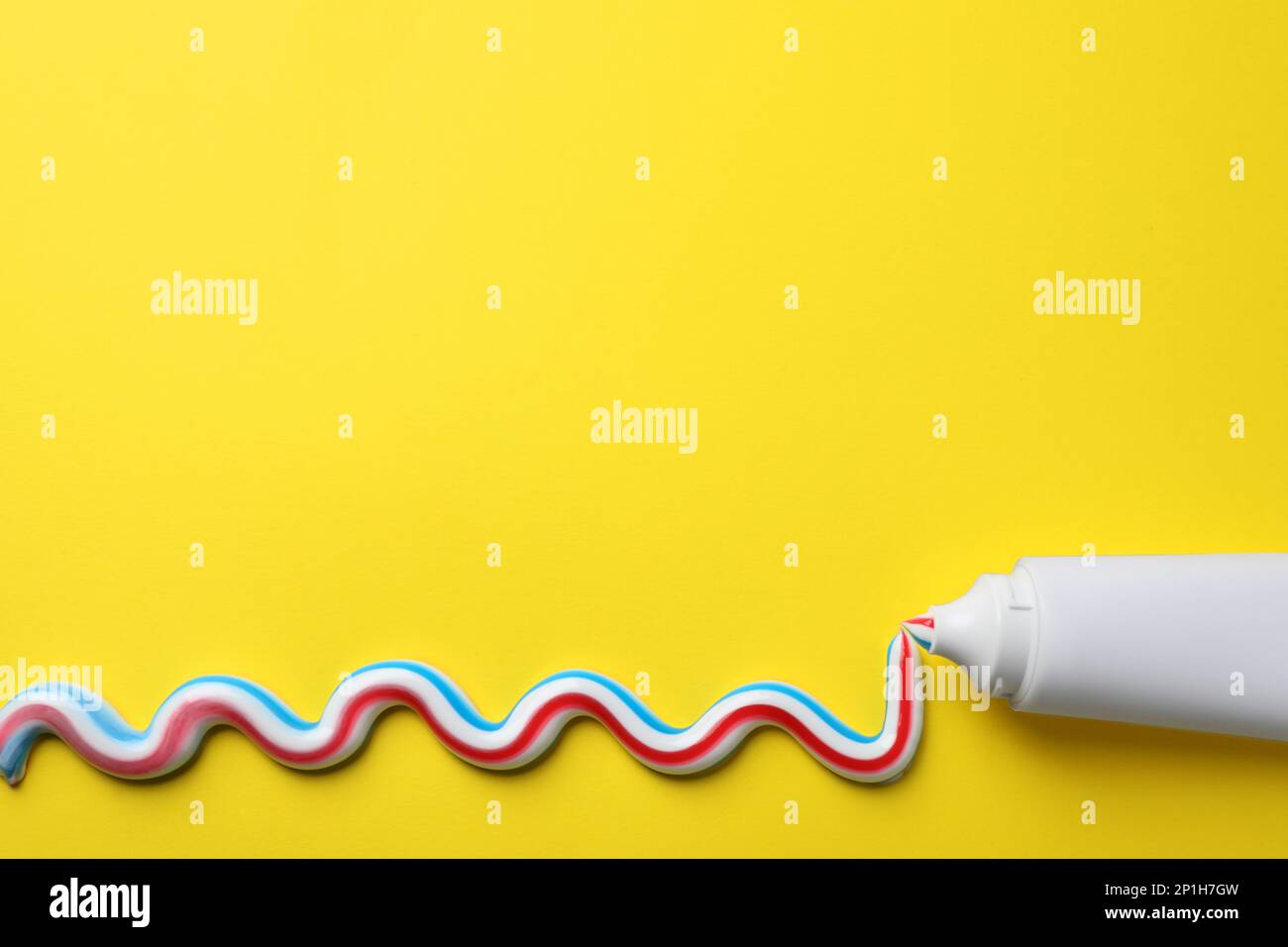 Blank tube with squeezed out toothpaste on yellow background, flat lay ...
