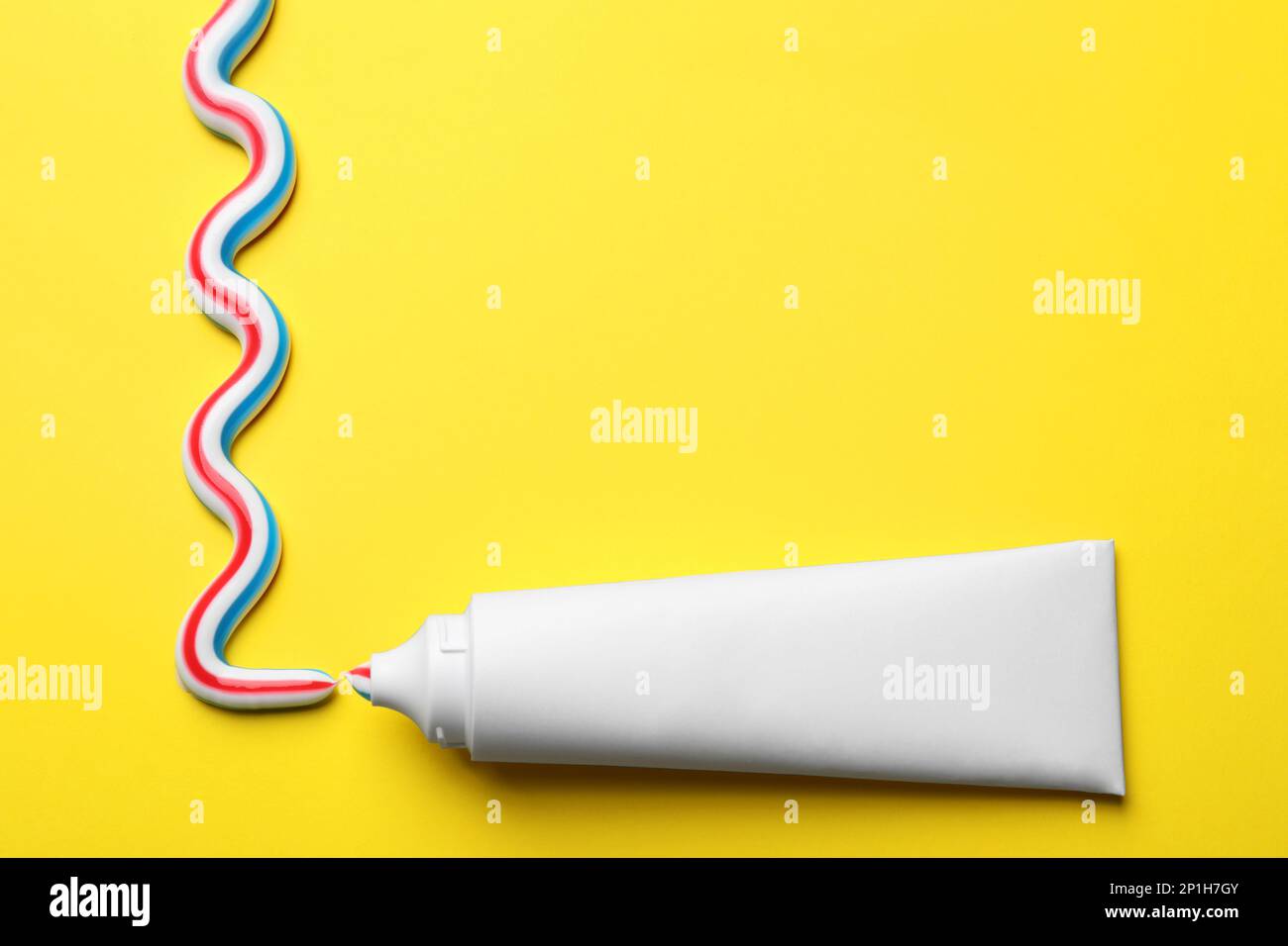 Blank tube with squeezed out toothpaste on yellow background, flat lay ...
