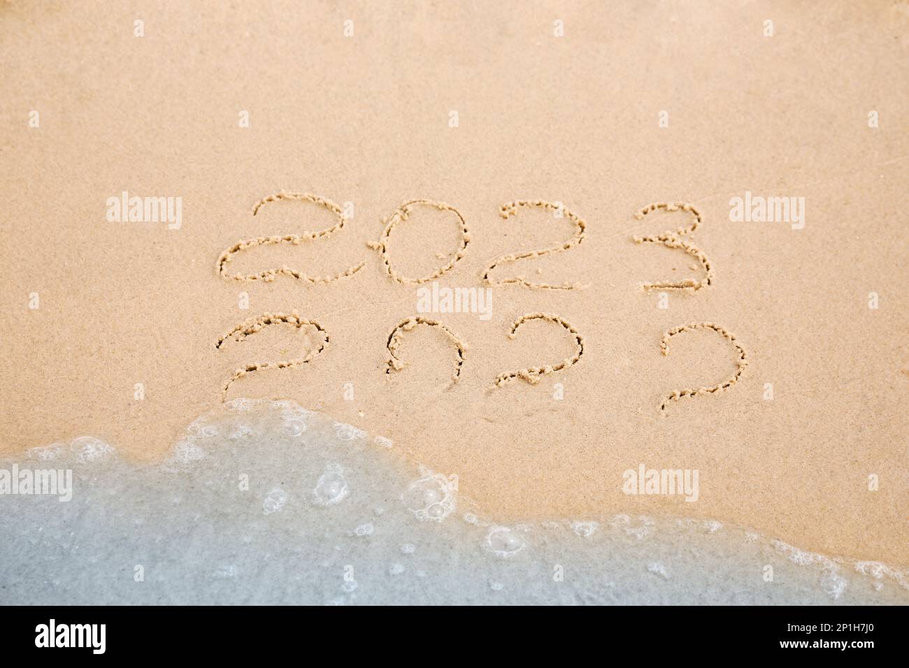 Dates written on sandy beach. 2022 washed by sea wave as New 2023 Year ...