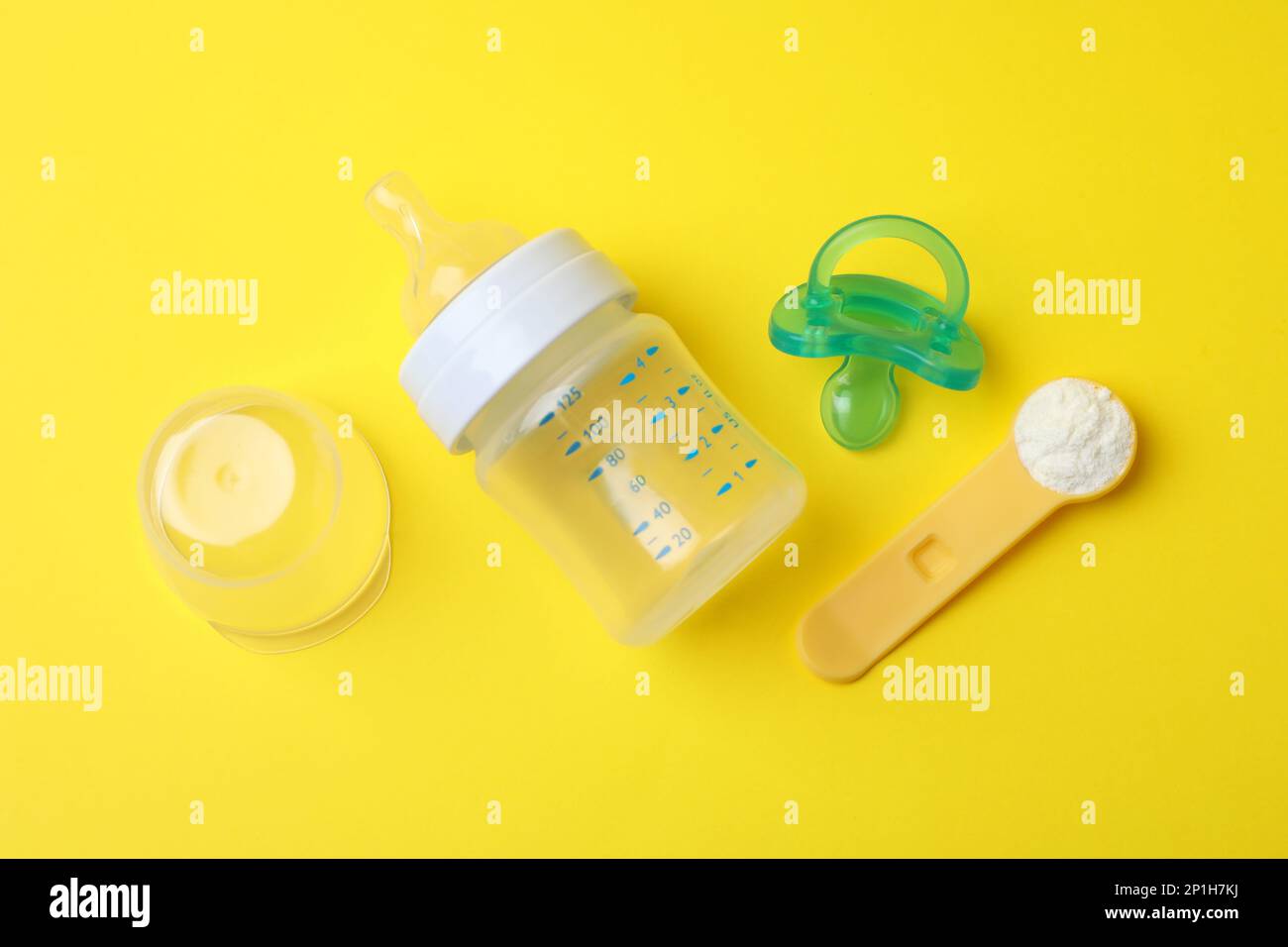 Flat lay composition with powdered infant formula on yellow background ...