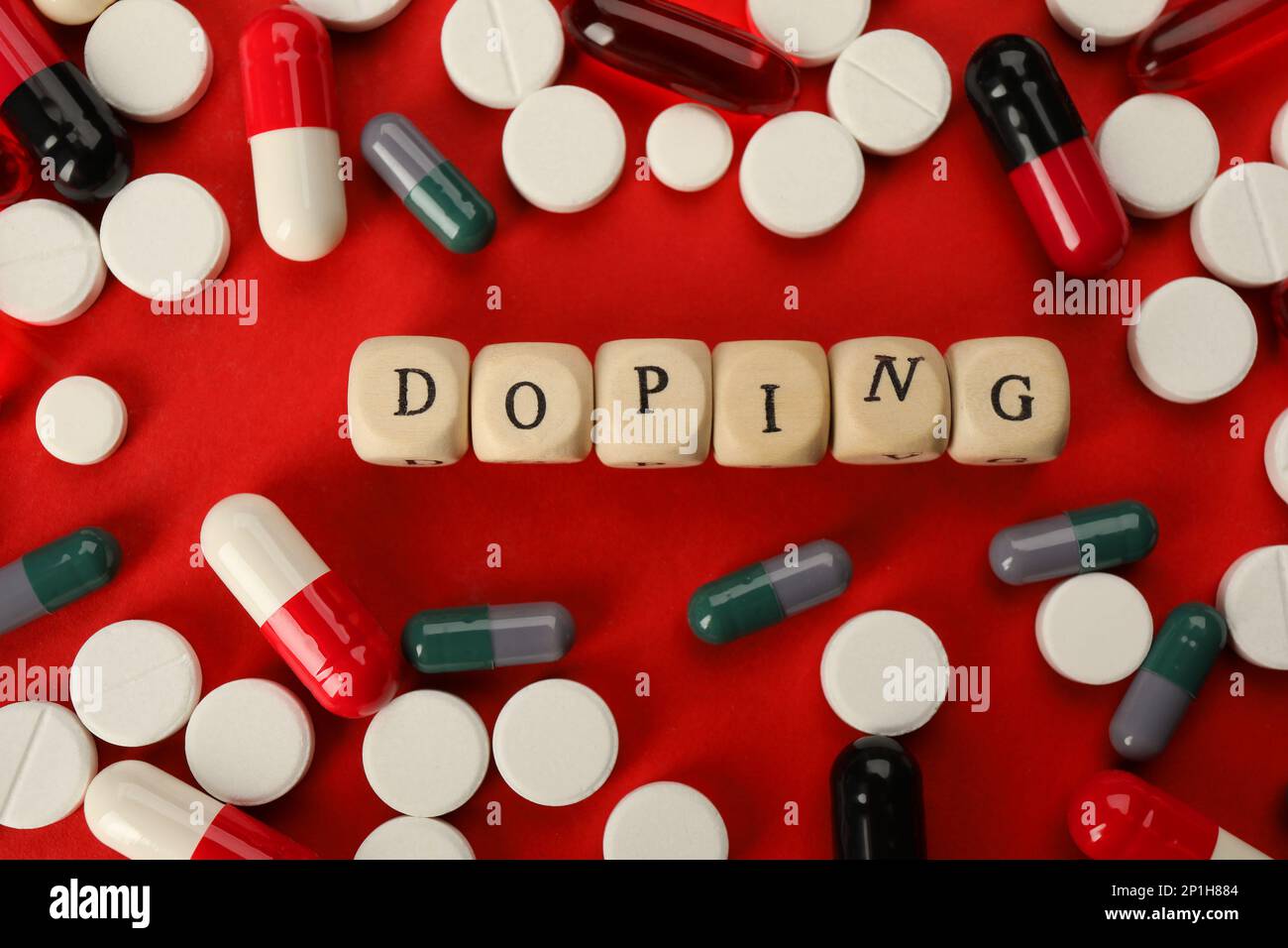 Wooden cubes with word Doping and drugs on red background, flat lay ...