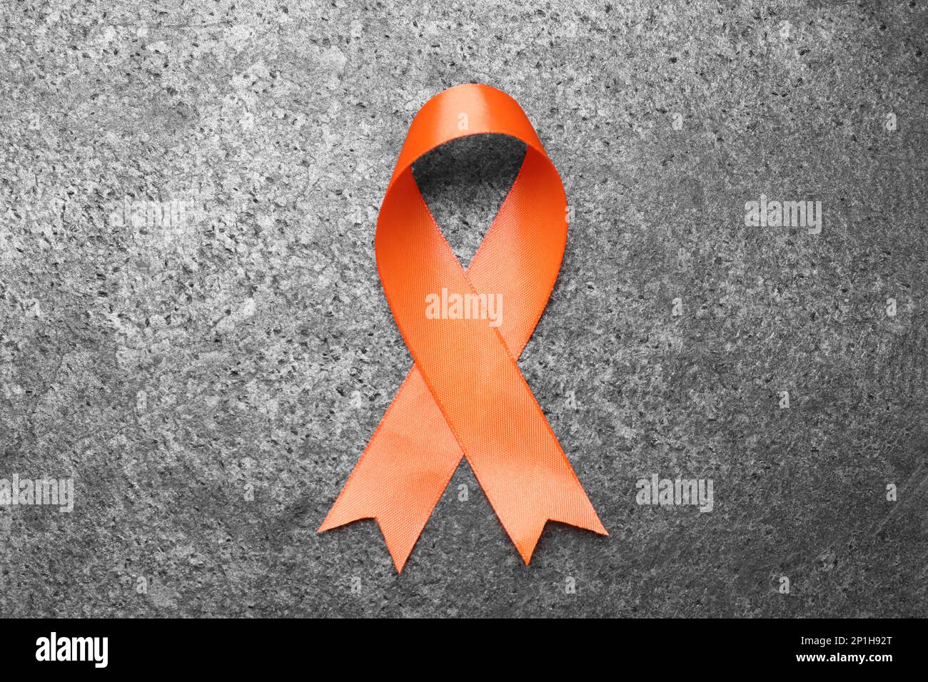 Orange ribbon on grey table, top view. Multiple sclerosis awareness ...