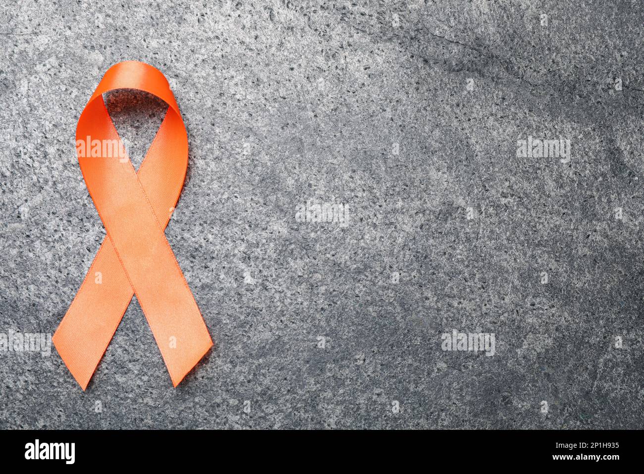 Orange ribbon on grey table, top view with space for text. Multiple ...