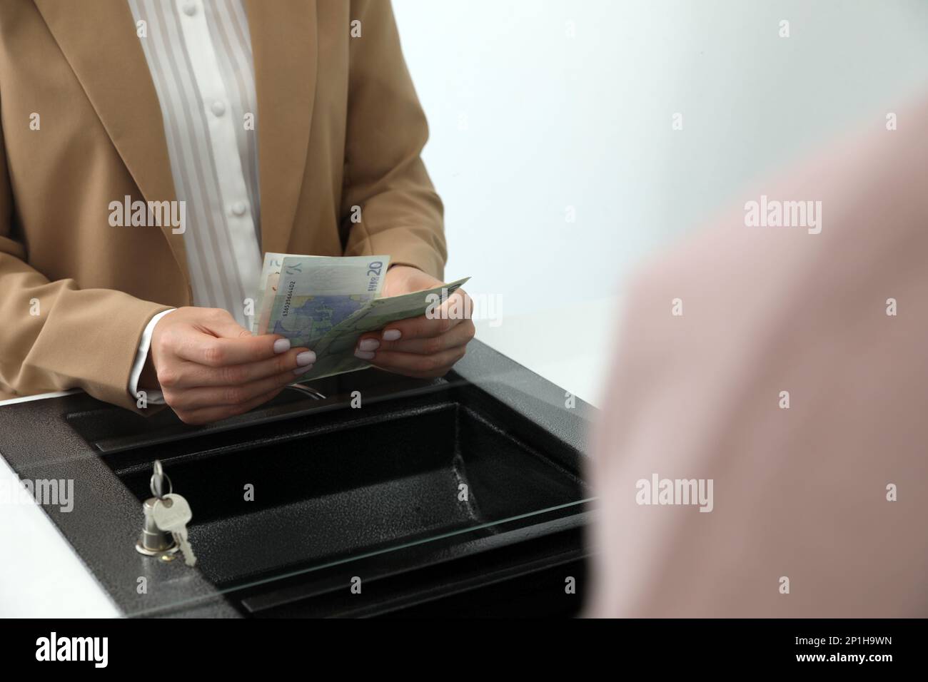 Cashier with money at currency department window in bank, closeup Stock ...