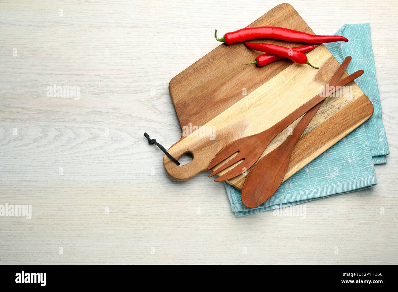 Cutting board with peppers and cooking utensils on white wooden table ...