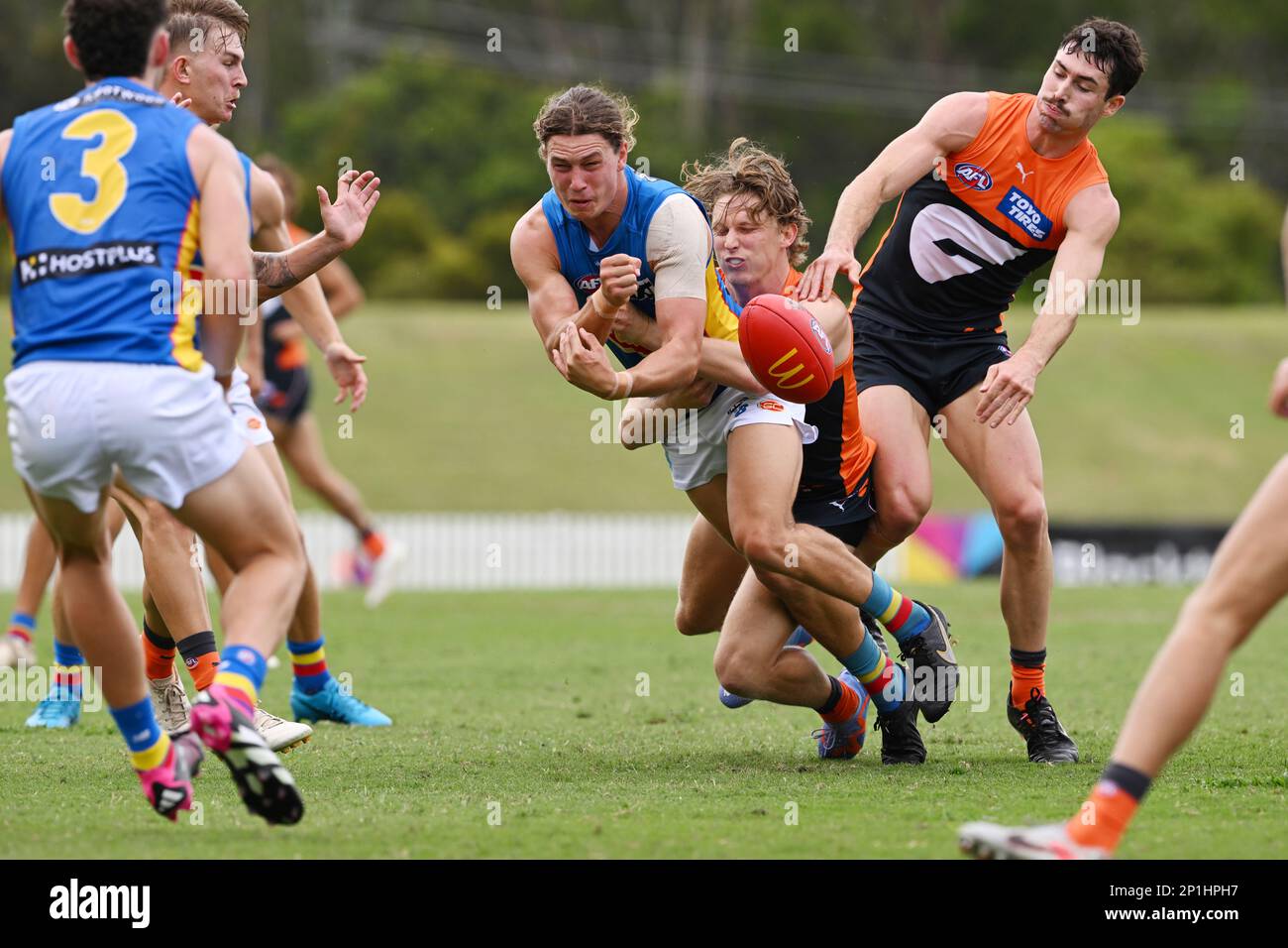 Tom Berry of the Suns hand balls as he’s tackled by Lachie Whitfield of ...