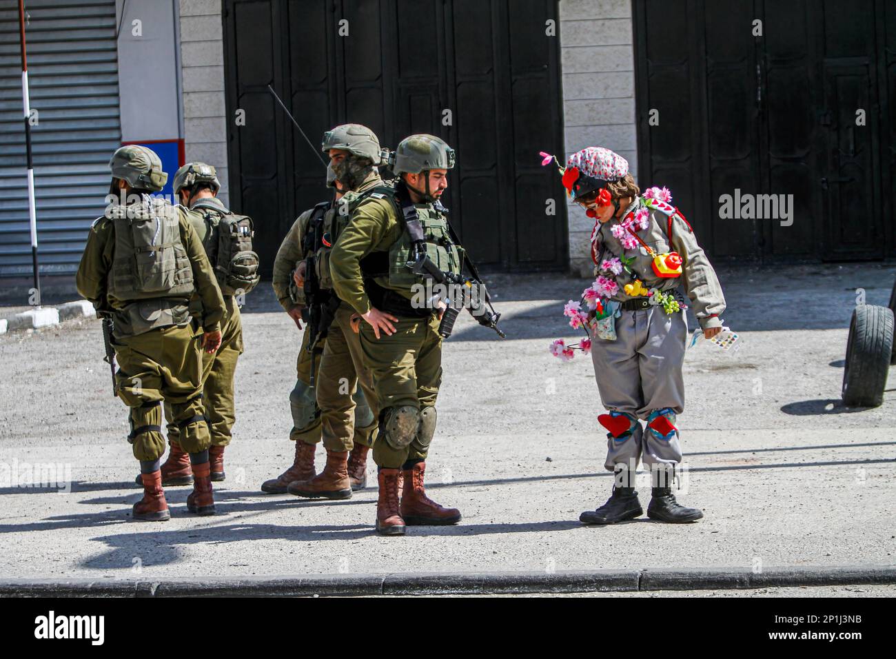An Israeli activist dressed as a clown plays in front of a foot patrol ...
