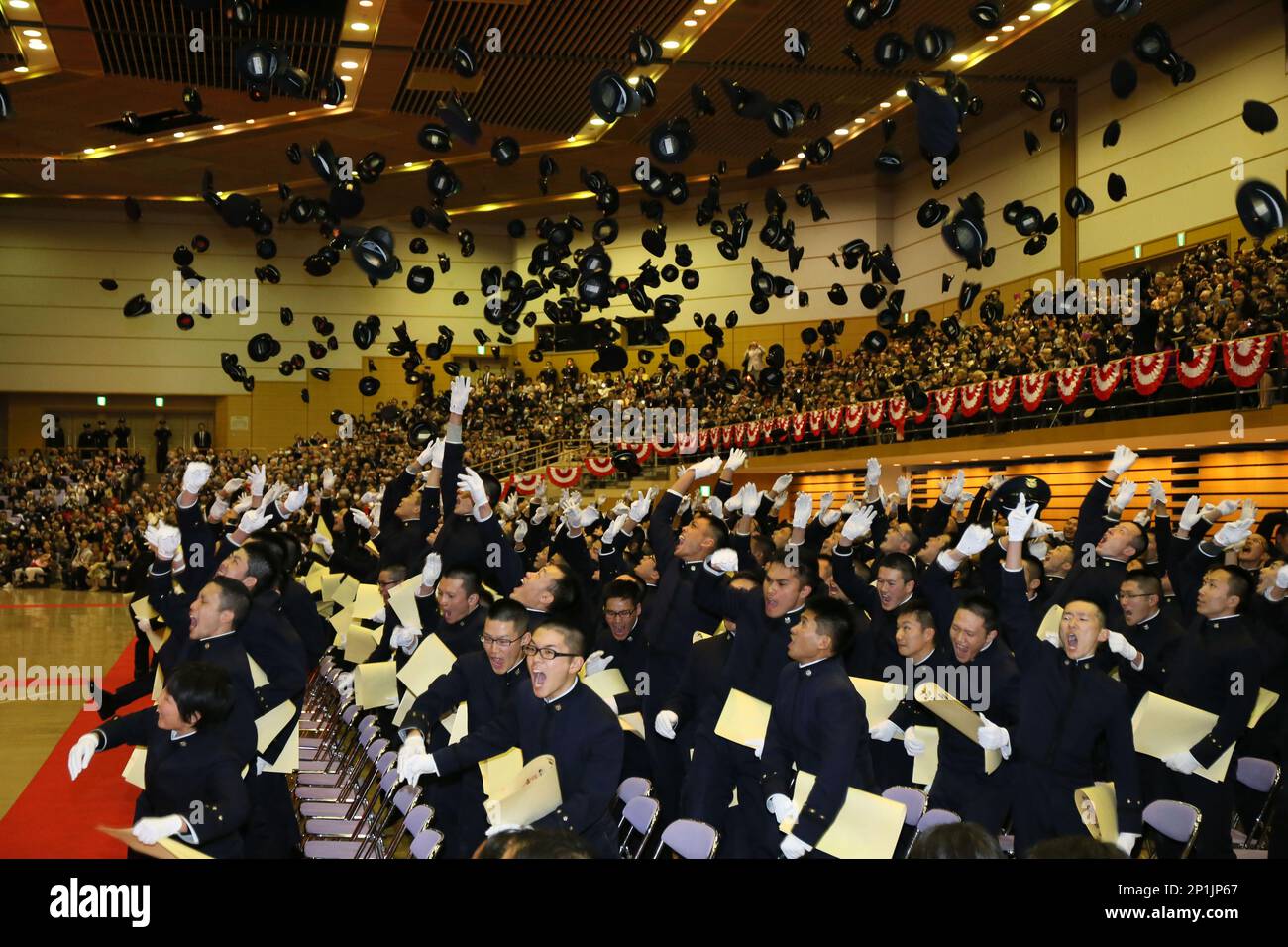 Graduates of the National Defense Academy throw their caps into the air ...