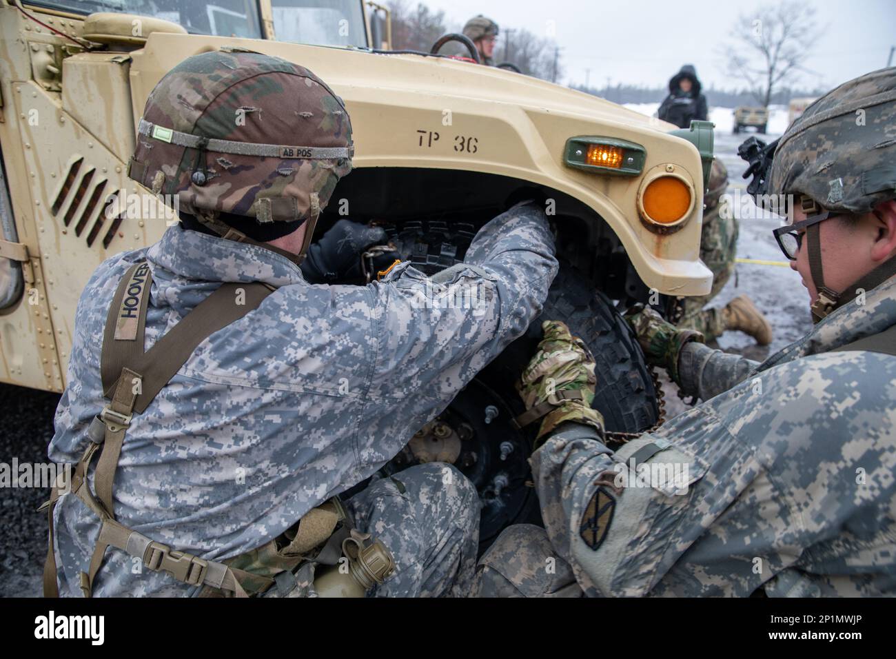 10th Mountain Soldiers work together in order to put snow chains on a ...