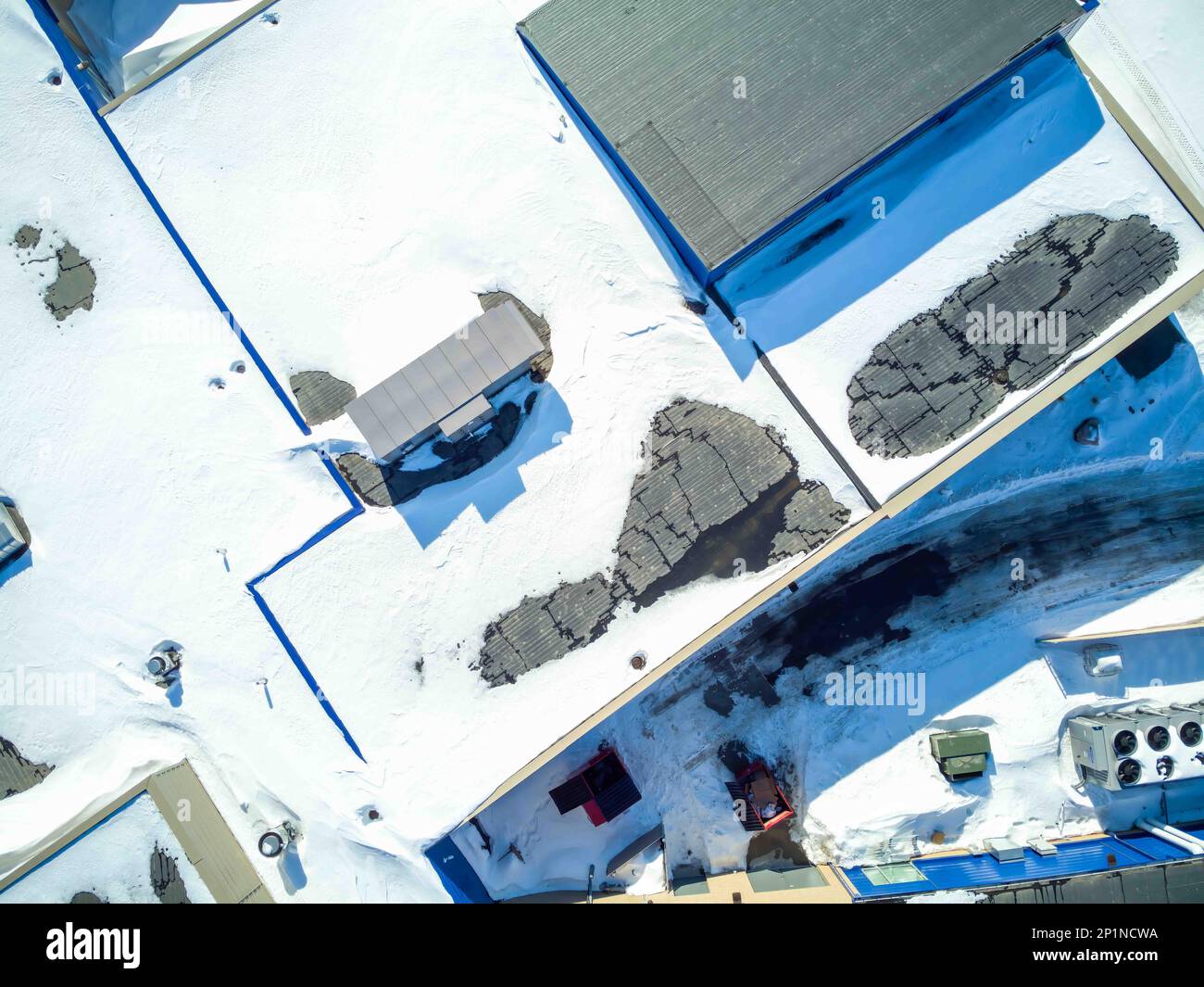 Elevated overhead drone view of a flat roofed building with snow load ...