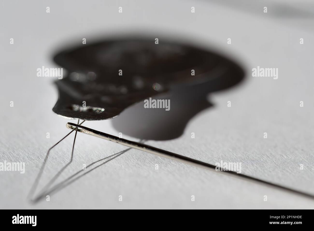 Sewing needle threader tool in use and a single black string Stock ...