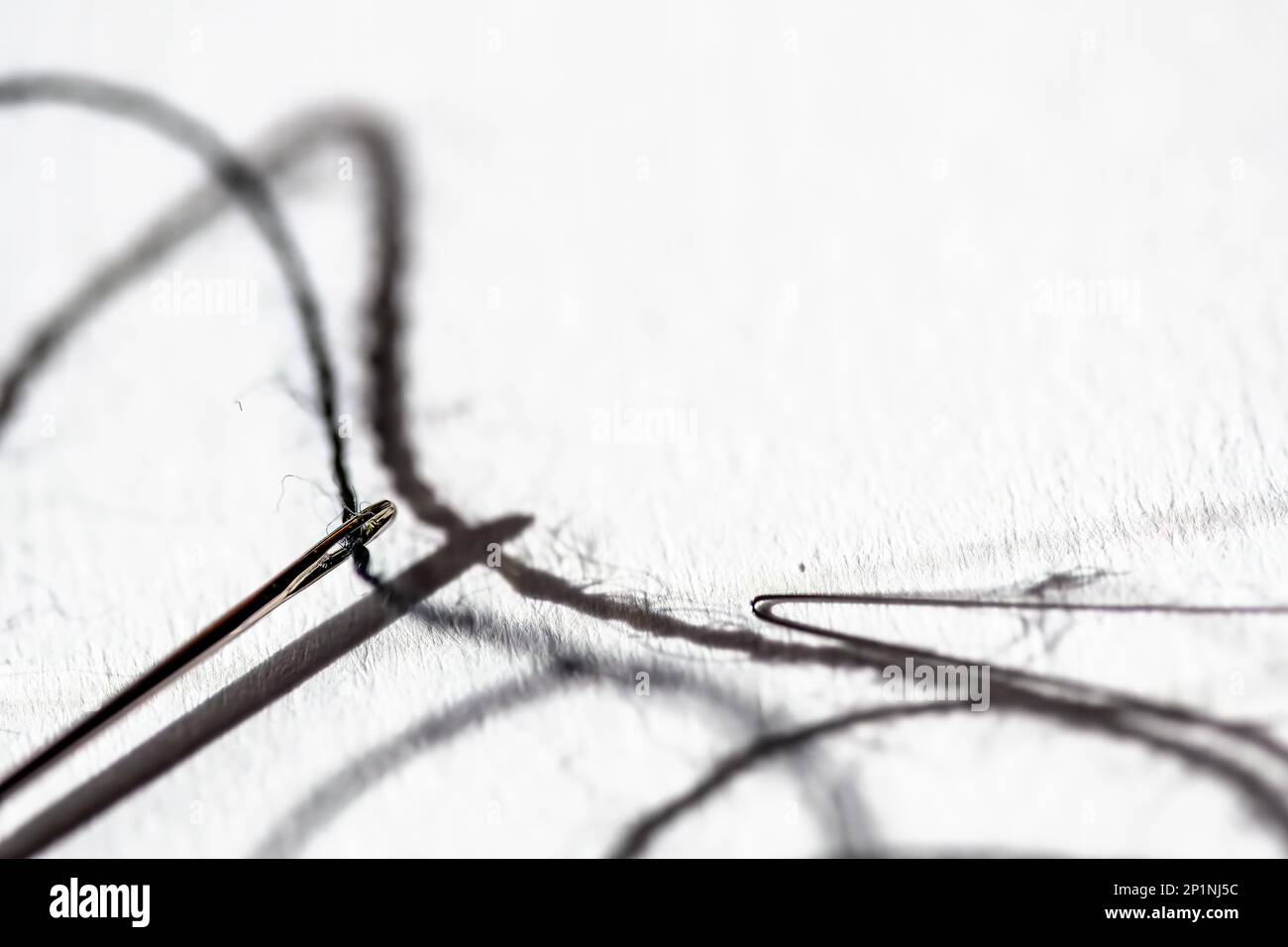 Sewing needle threader tool in use and a single black string Stock ...