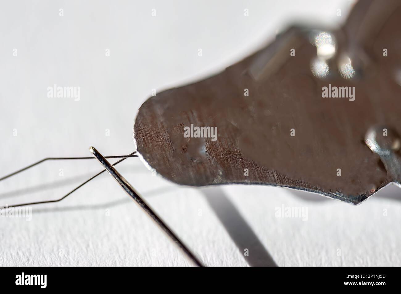 Sewing needle threader tool in use and a single black string Stock ...