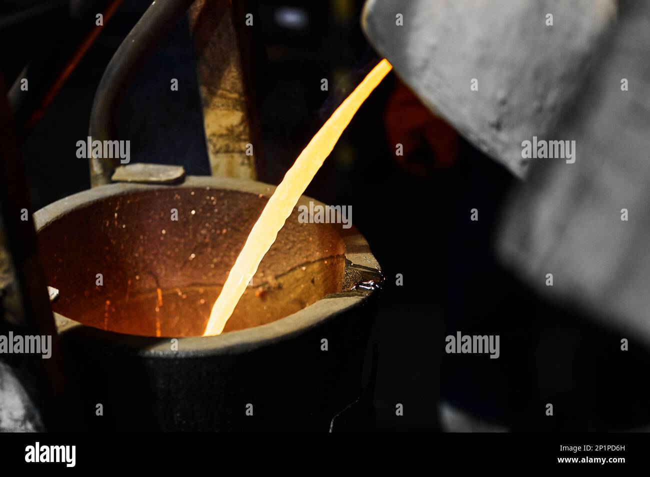 Melted liquid metal flow poured down from pot in furnace Stock Photo ...