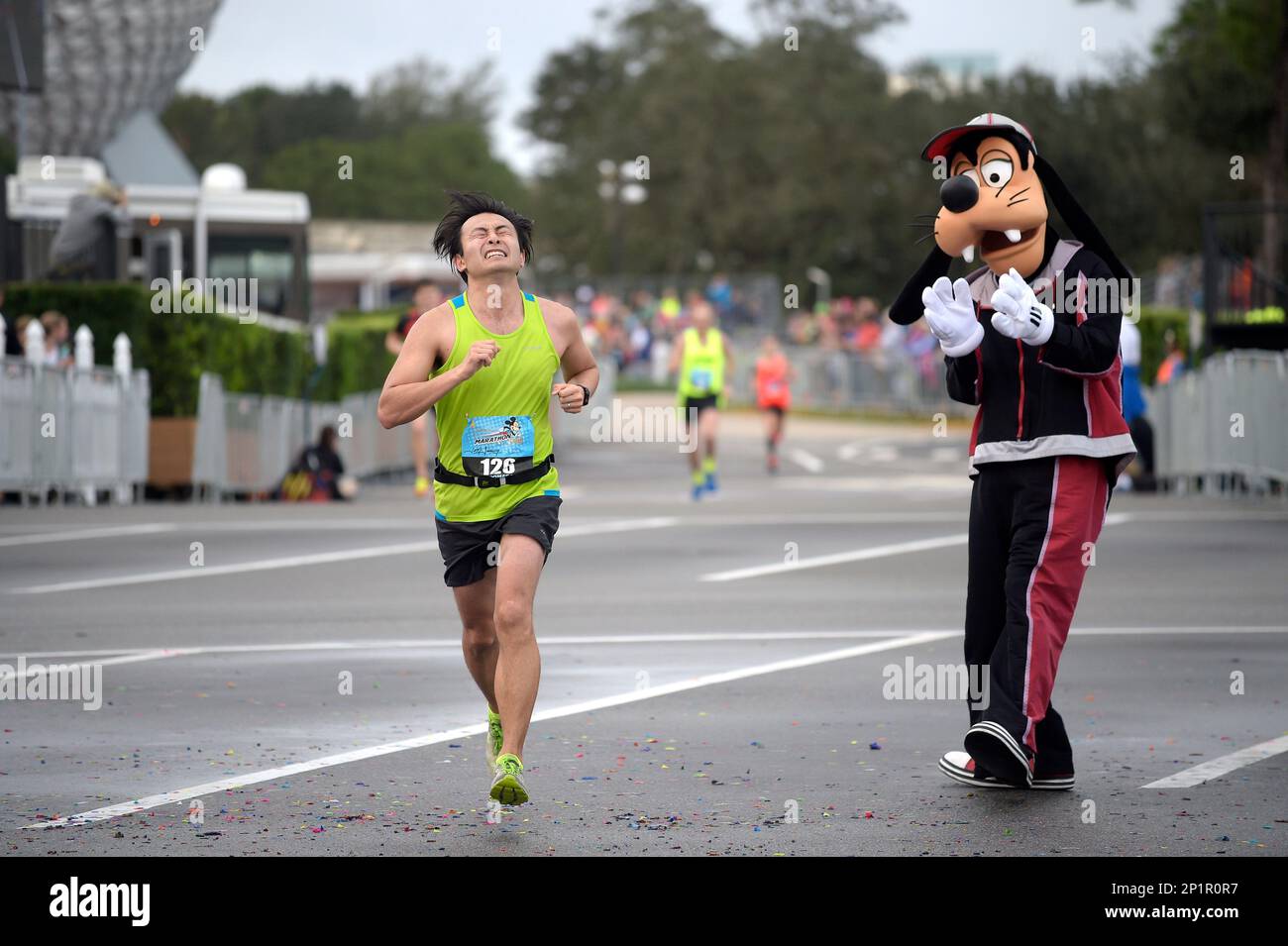 An actor dressed as Goofy, right, greets runners at the finish line ...