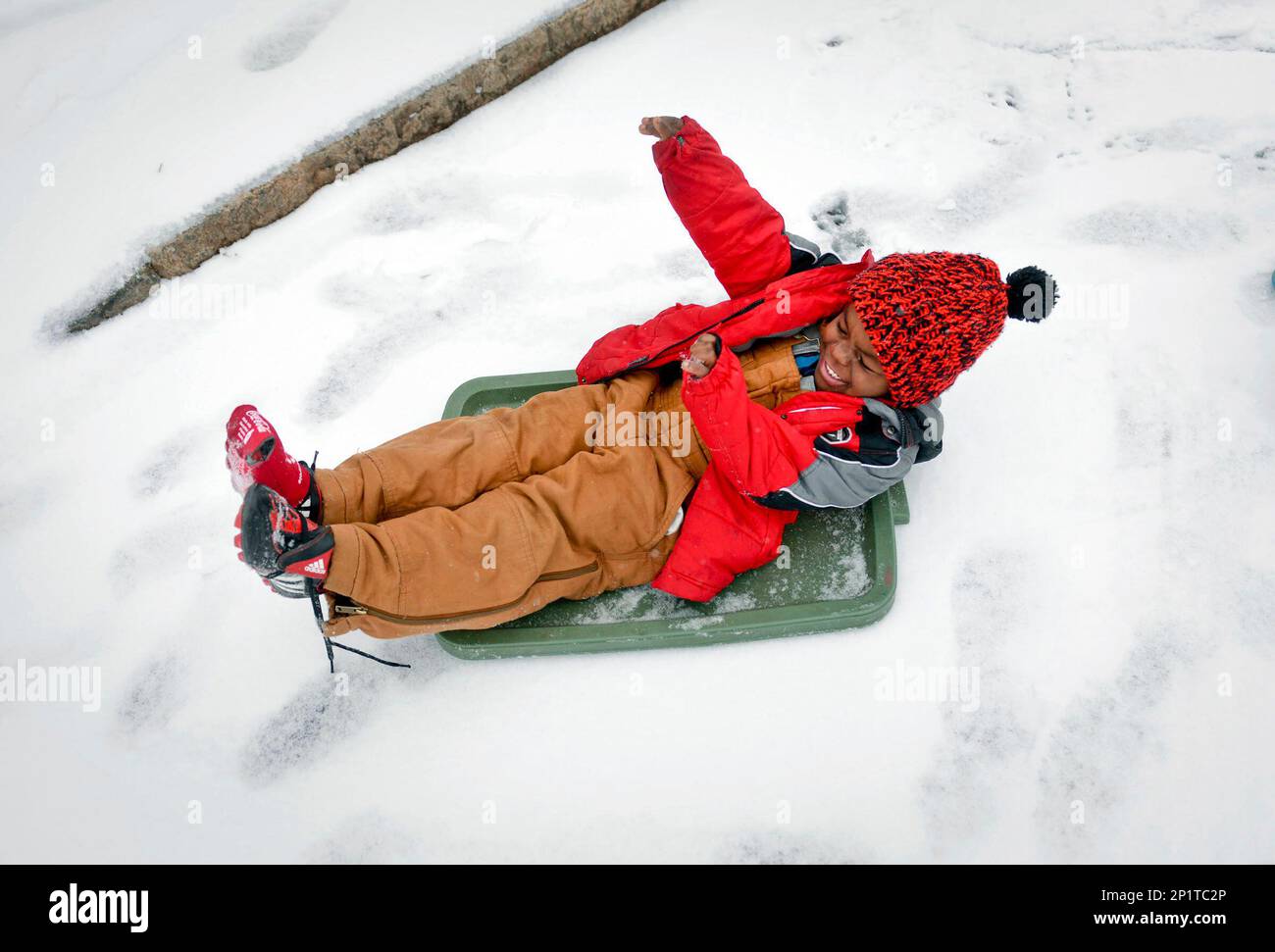 Donnell Glover, 5, sleds down his street on a large container lid ...