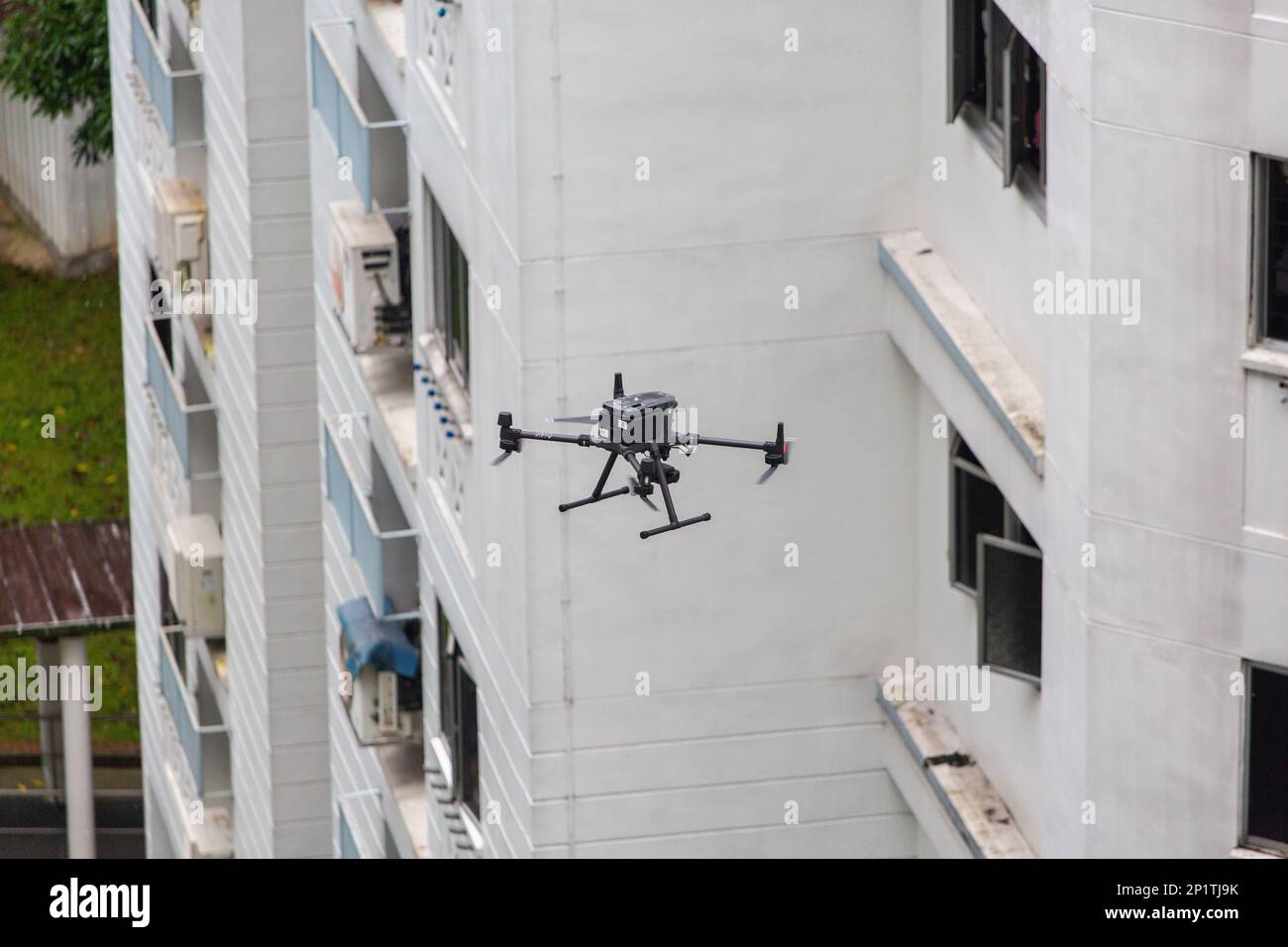 A drone in mid-air flight is conducting a building inspection to ...
