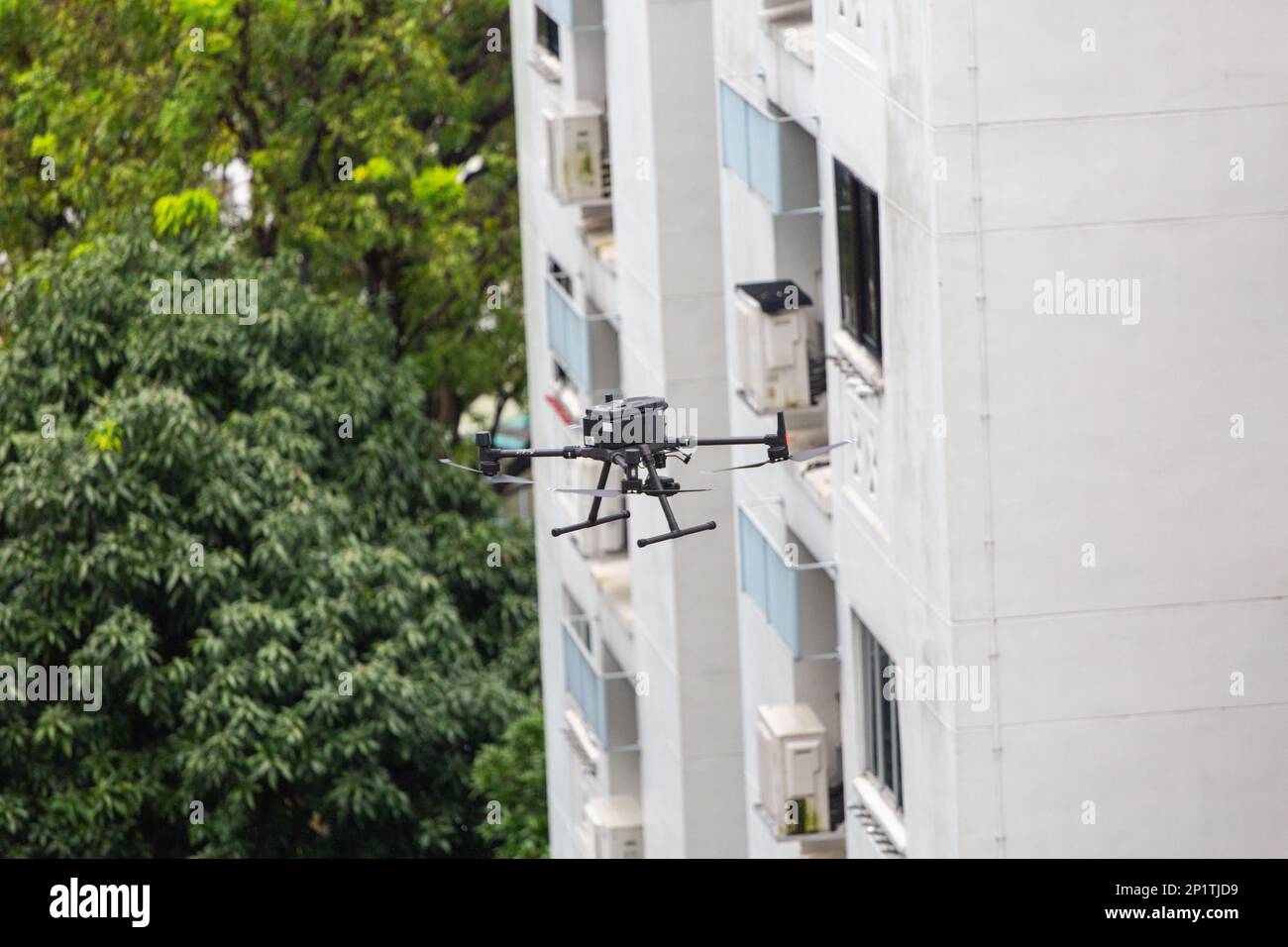 A drone in mid-air flight is conducting a building inspection to ...