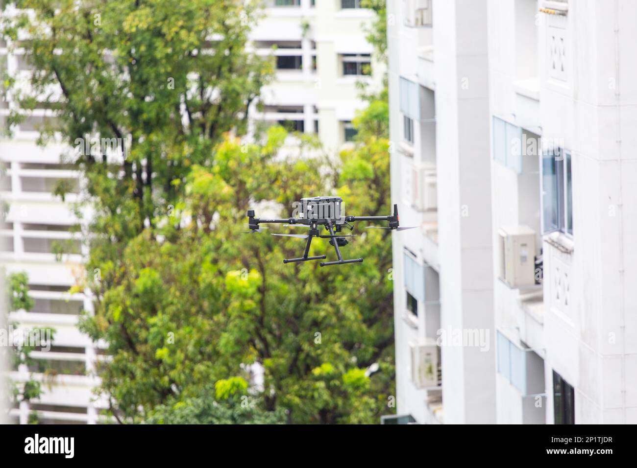 A drone in mid-air flight is conducting a building inspection to ...