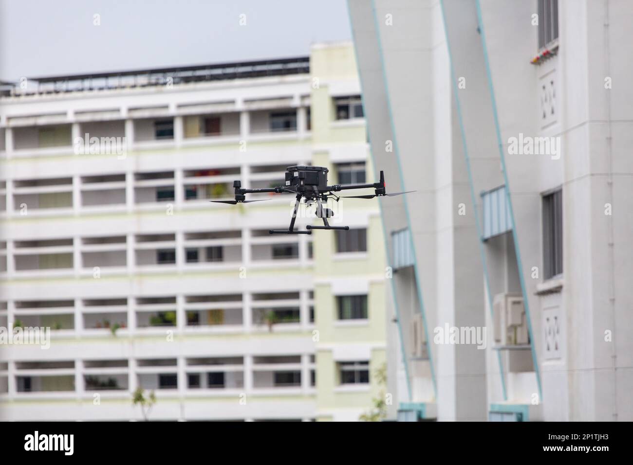 A drone in mid-air flight is conducting a building inspection to ...