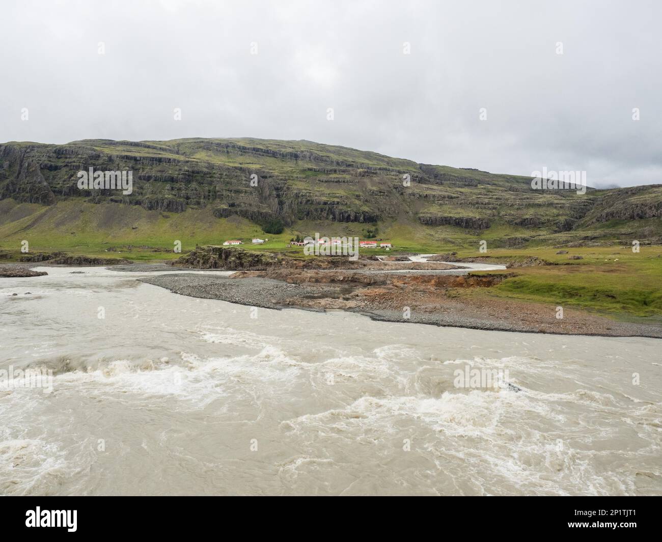 Glacier river and farm in front of mountain range, near Hoefn, East ...