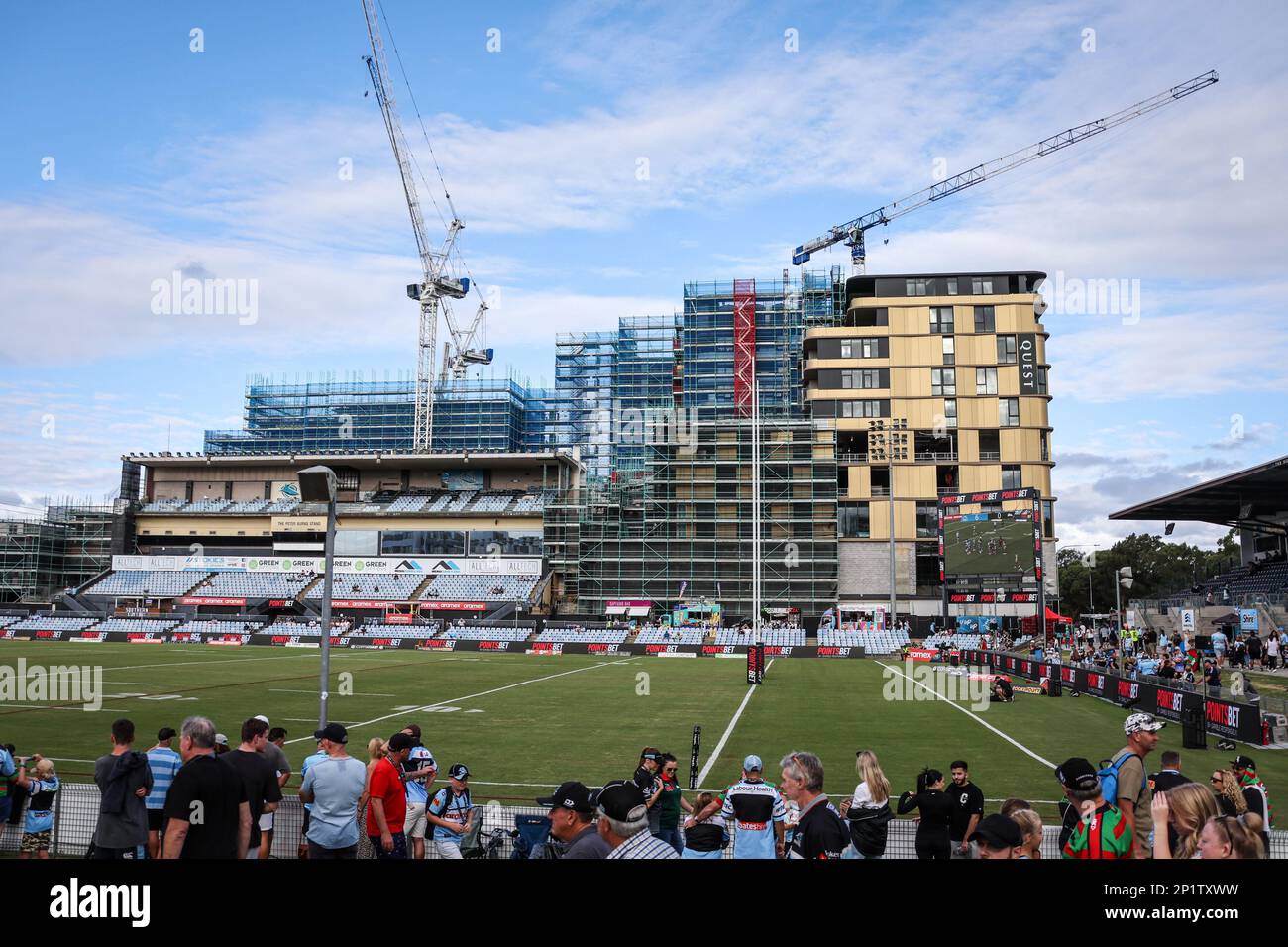 Cranes stand atop buildings under construction as crowds gather ahead ...