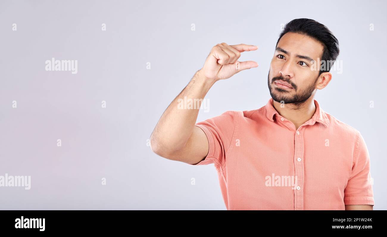 Hand gesture, size and mockup with a man in studio on a gray background ...